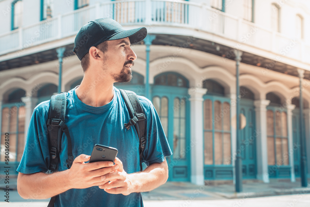 Young tourist man with backpack looking smartphone while touring a ...