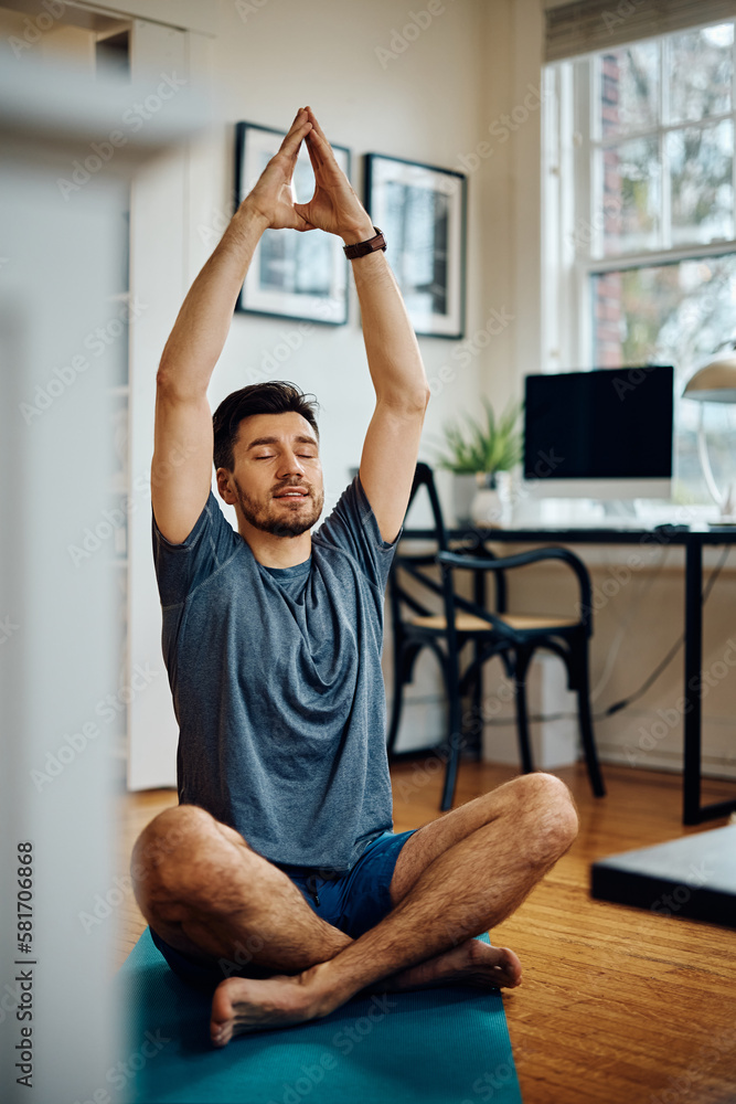 Athletic man doing breathing exercise while practicing Yoga at home ...