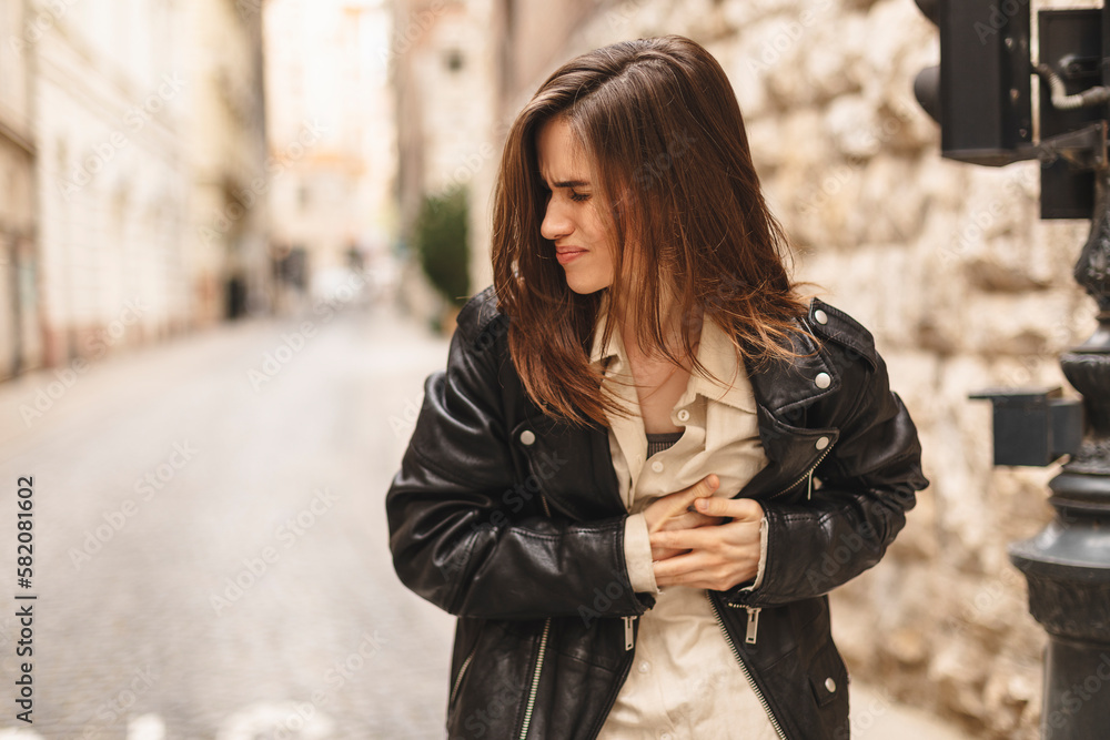 Foto de Stock Woman standing outdoor with strong chest pain and hands ...