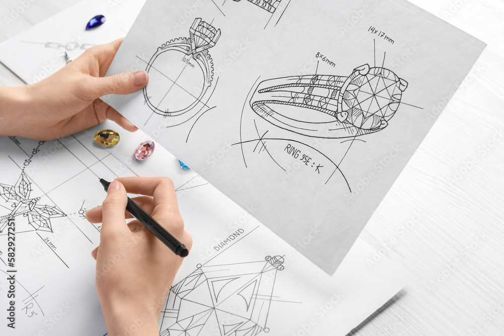 Jeweler with sketches of elegant jewelry at white wooden table, closeup ...
