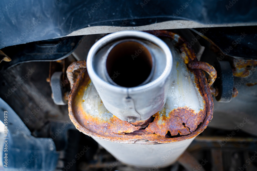 Rusty car exhaust muffler with a through hole, close-up. Corrosion on a ...