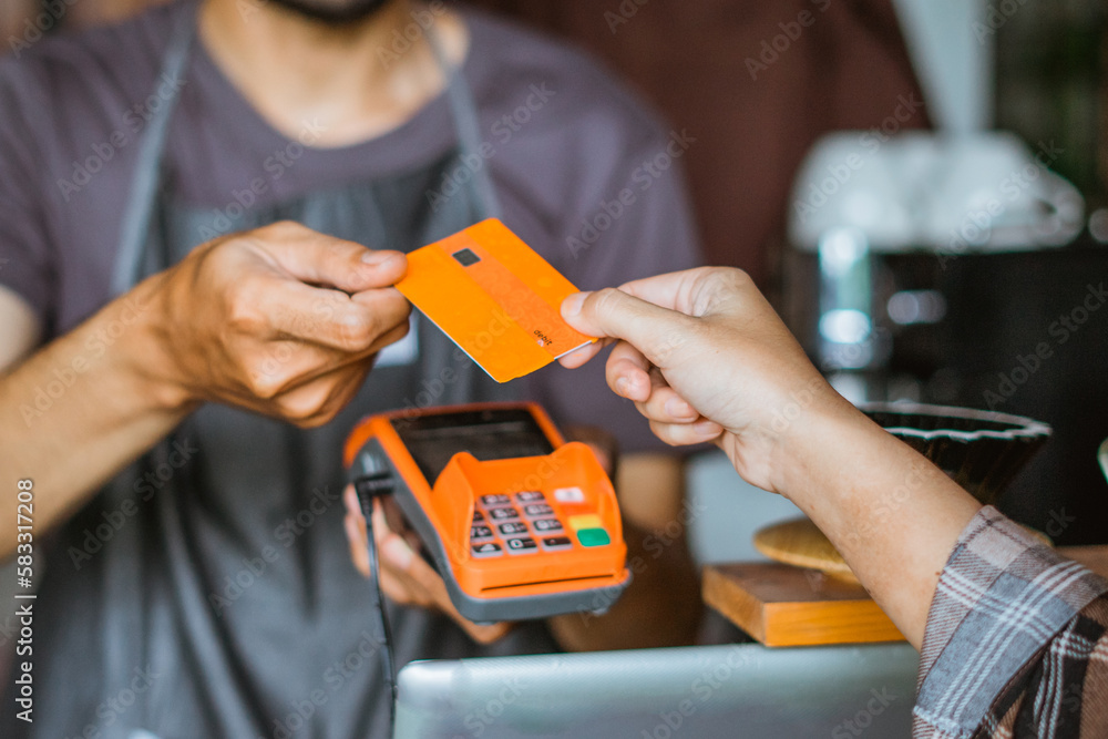the hand of the male barista receiving the credit card from the ...