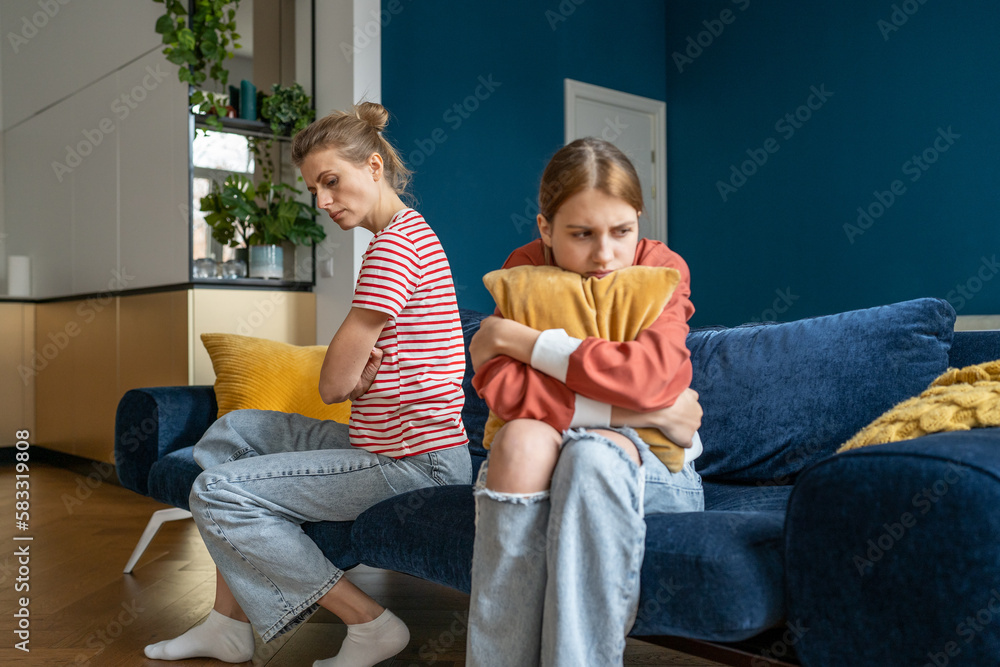 Upset teenage daughter and young woman mother sitting separately in ...