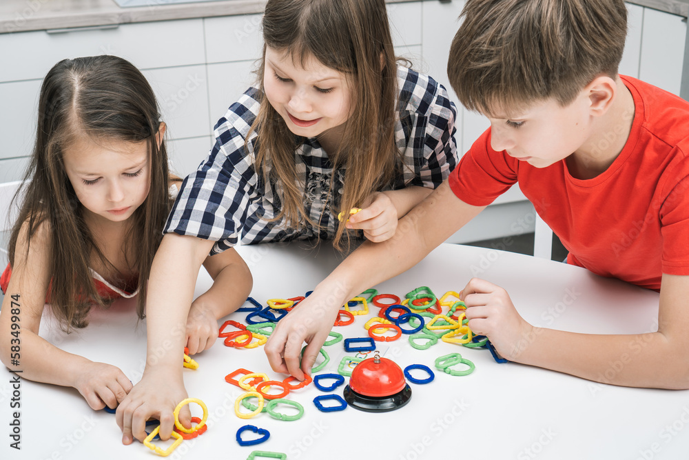 Smiling, pensive children of boy and girls connecting colorful chain ...