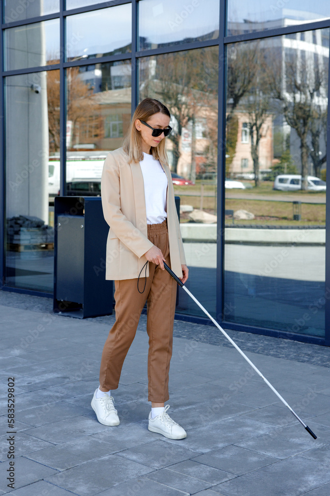 Caucasian woman with visual disability walking near glass wall of ...