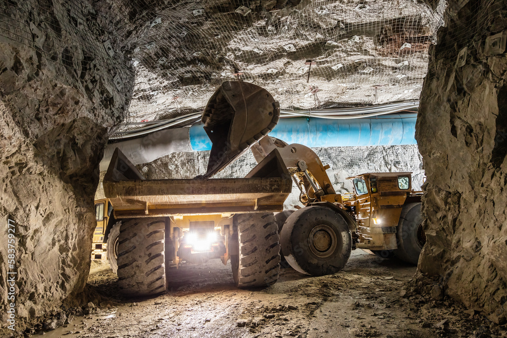 Mining load truck being filled with ore by an excavator underground in ...