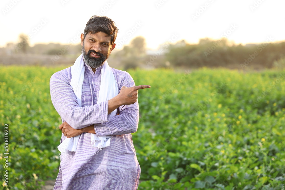 Happy rural Indian a farmer pointing at his right side while looking at ...