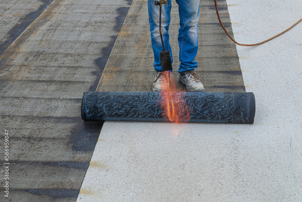 workers insulating rooftop with bitumen membrane. Waterproofing details ...