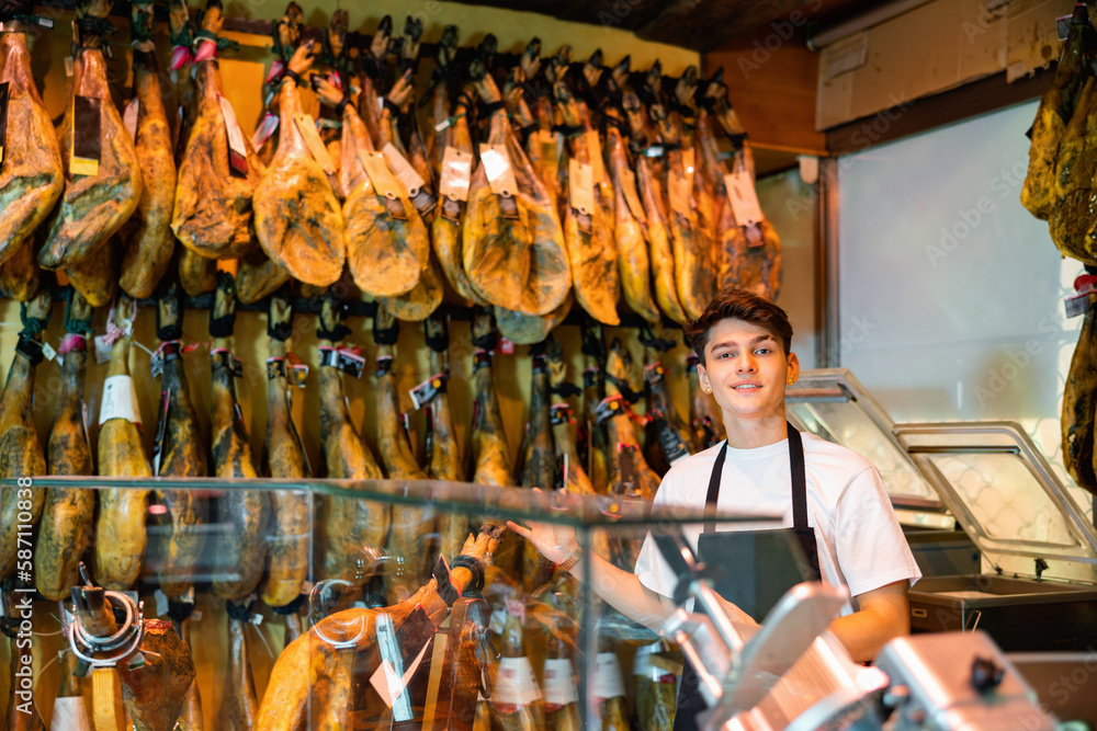 Foto de Stock Smiling young salesman in black apron standing near rack ...