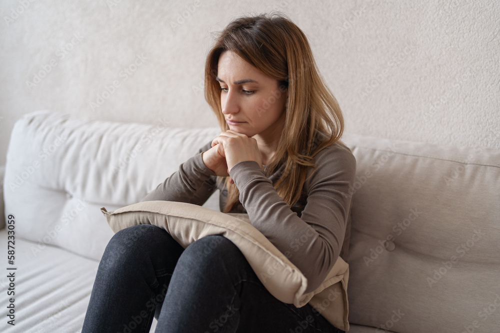 Depression concept. Portrait of sad woman sitting on sofa at home ...