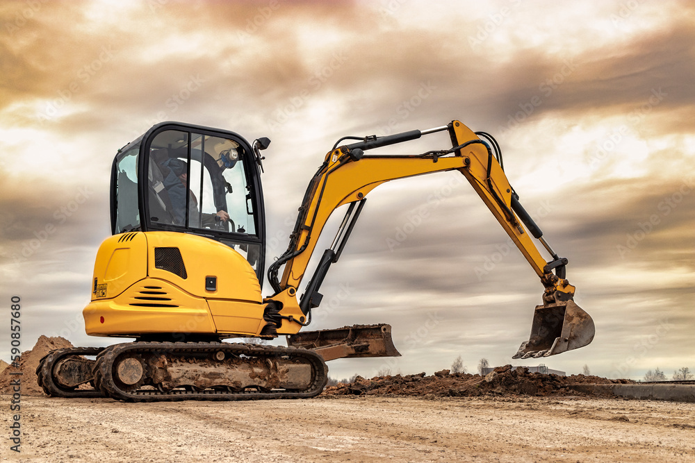 Mini excavator at the construction site on the edge of a pit against a ...