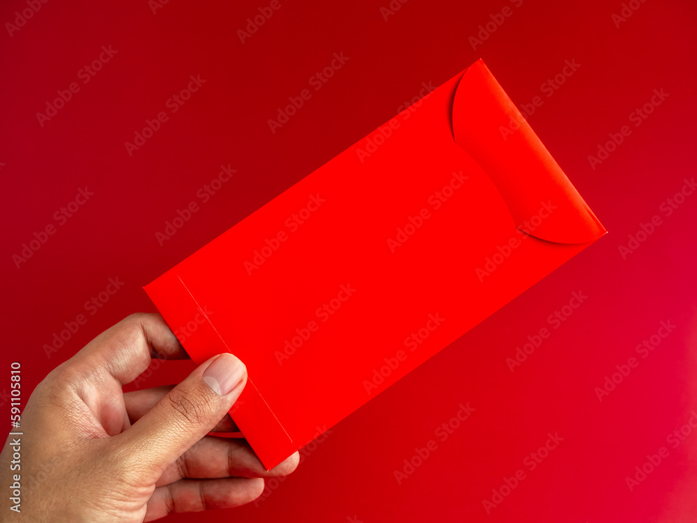 Hand holding a red envelope isolated on red background. Hongbao packet ...