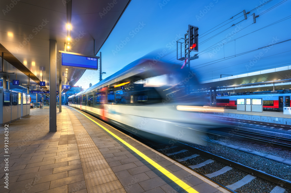 Blurred high speed train on the modern railway station at night in Graz ...