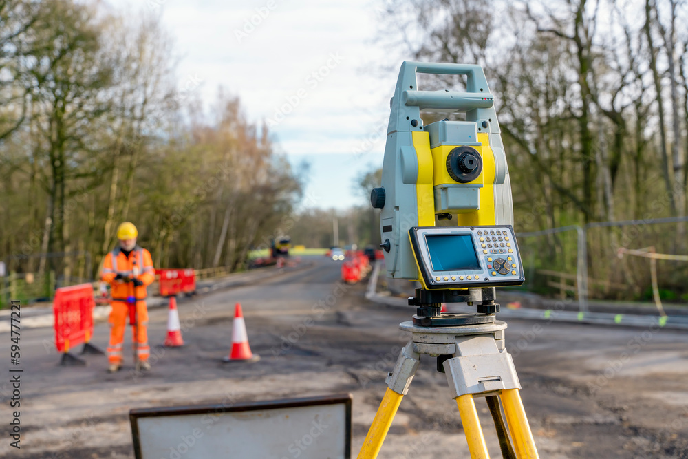 Site engineer operating his instrument during roadworks. Builder using ...