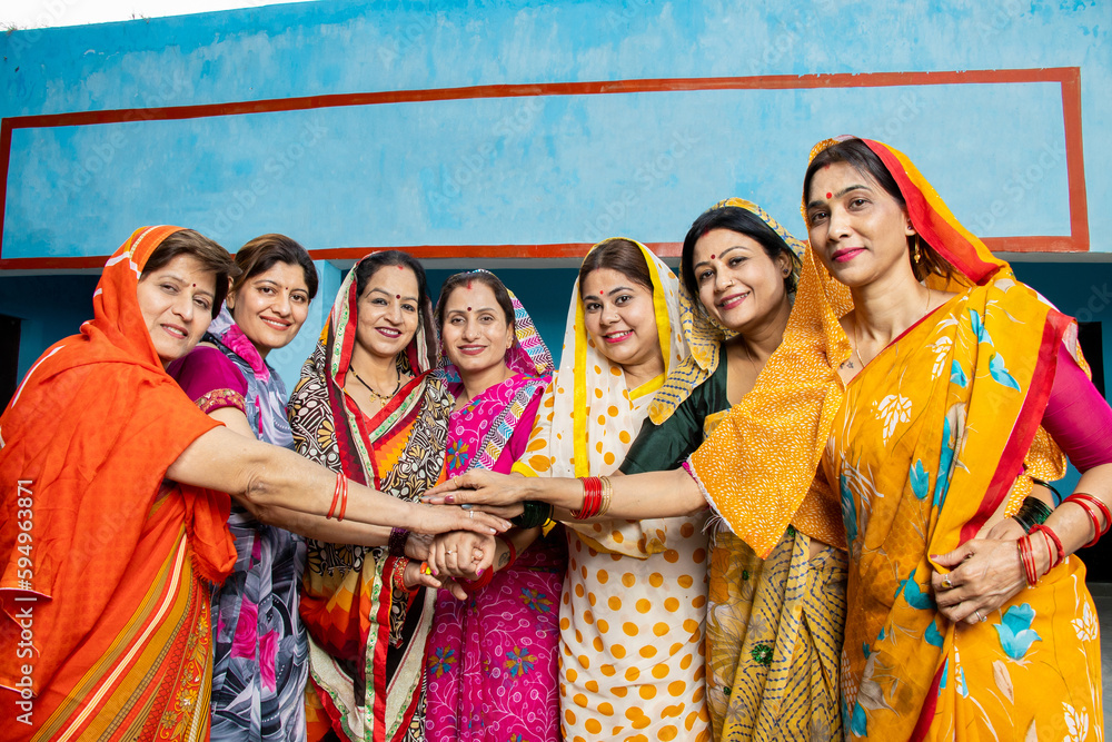 Group of happy young indian women wearing saree join hands with each as ...