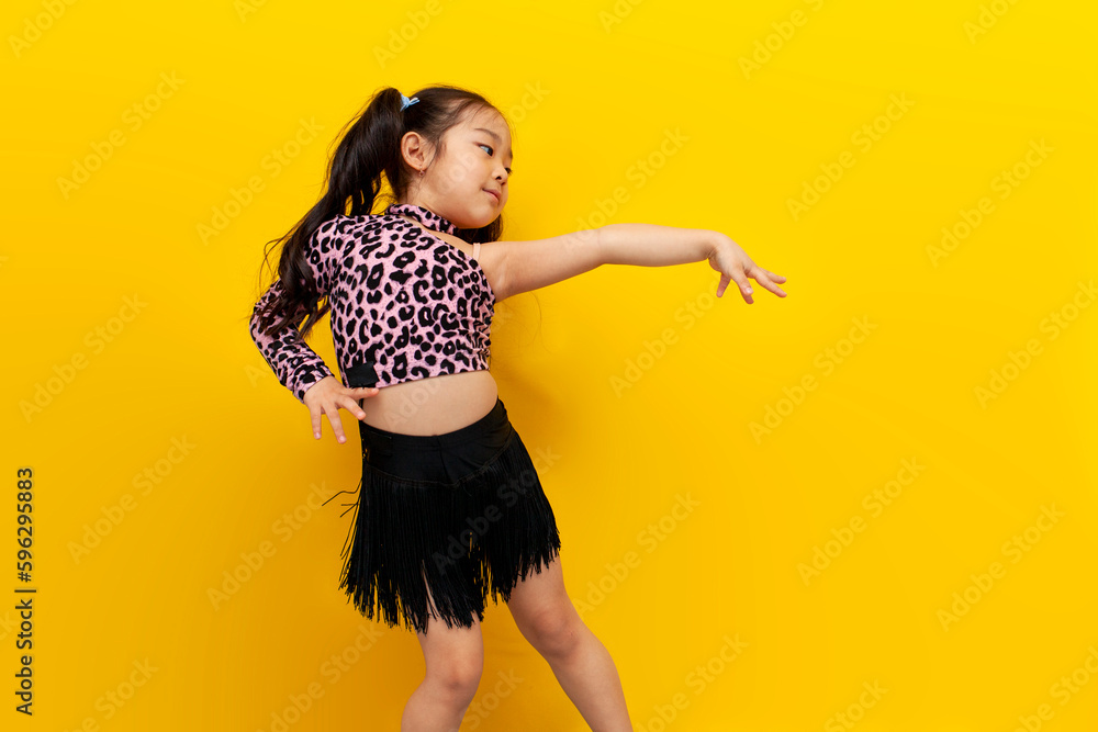 little asian girl in dance outfit dances chachacha on yellow isolated ...