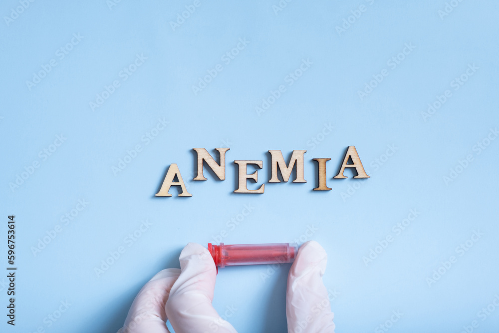 Anemia text with container for blood analysis in gloved hand flat lay ...