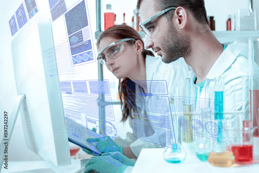 Two Young laboratory scientists look at the display and working with Futuristic Holographic ...
