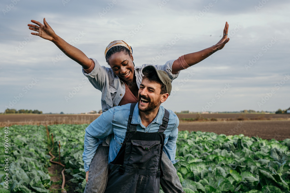 Smiling embraced diverse working couple having a piggyback ride and fun ...