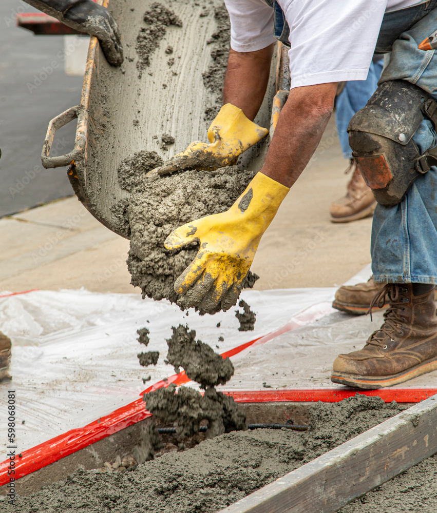 Wet cement off loaded by construction workers from a cement truck chute ...