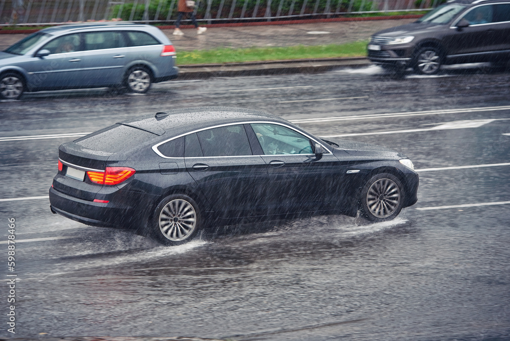 Foto Car driving fast on wet road, driving through puddle during heavy ...