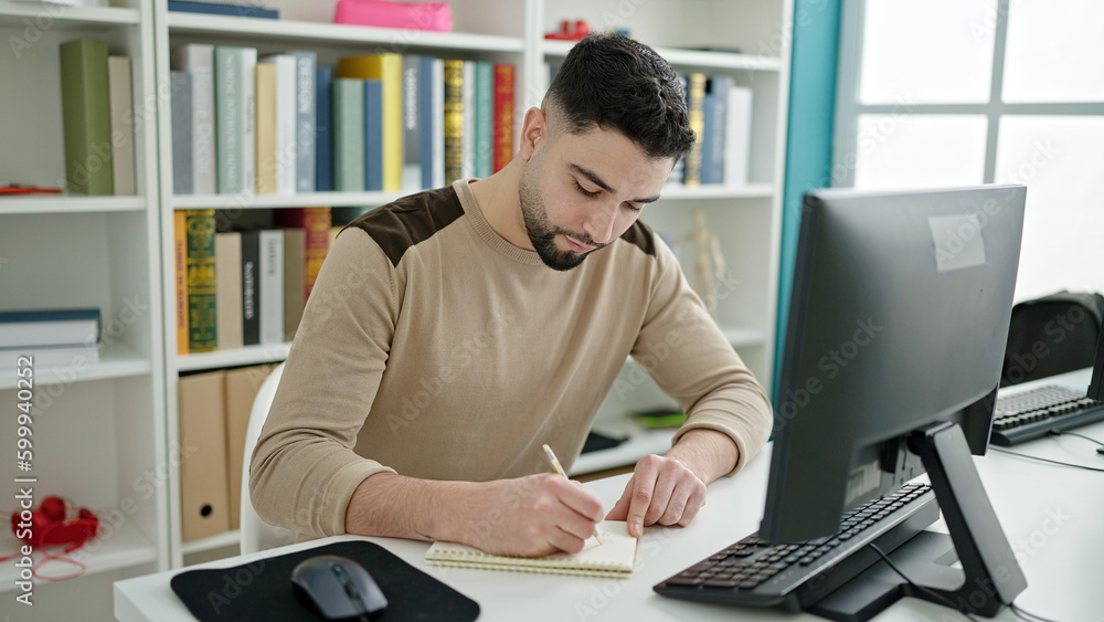 Young arab man student using computer writing on notebook at university ...
