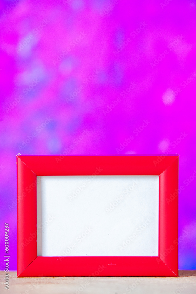 Vertical view of red empty picture frame standing on white table on ...
