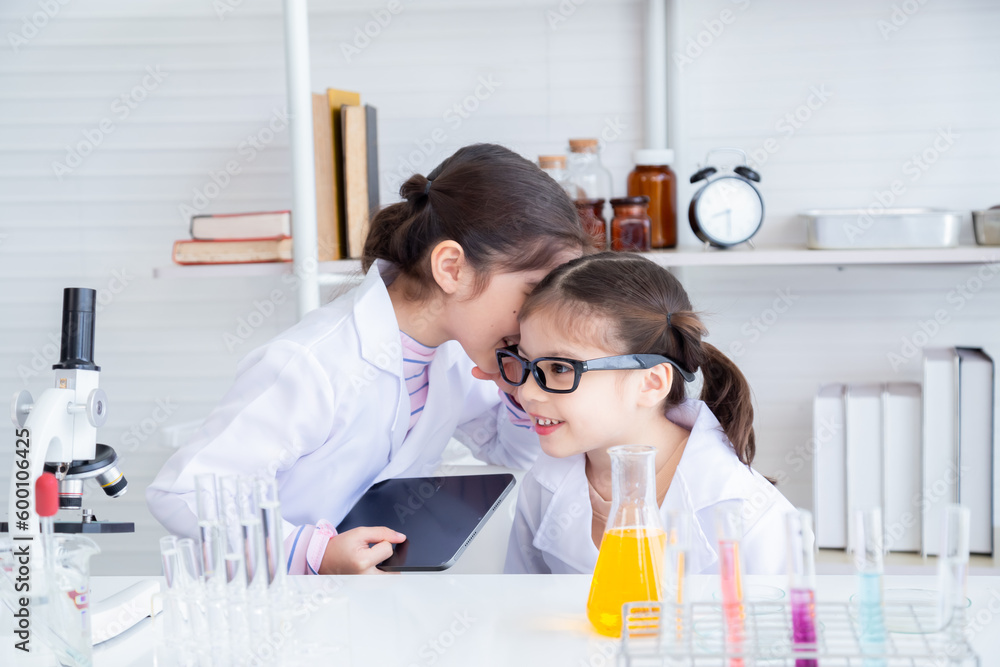 Elementary school children in white gown studying in science room, two ...