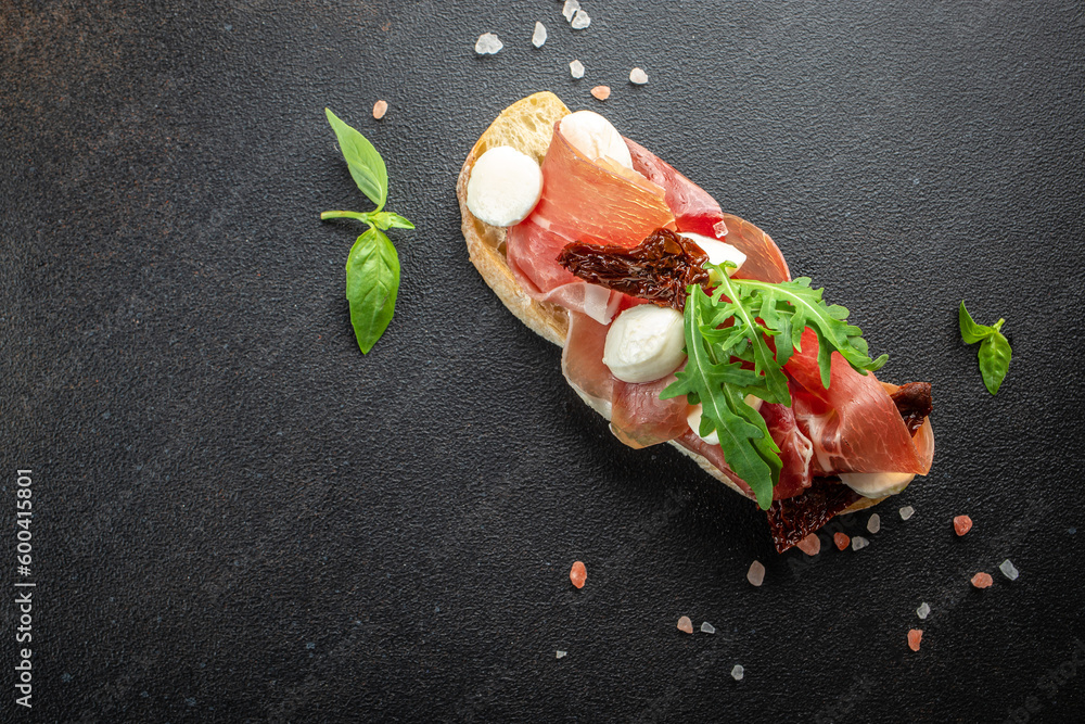 Spanish Tapas with cured Slices of jamon iberico ham with basil on a ...