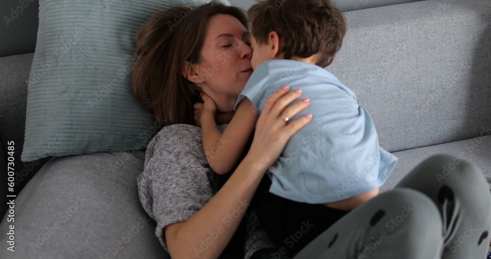 Four year old son hug mother closely gets kisses sitting on her belly ...