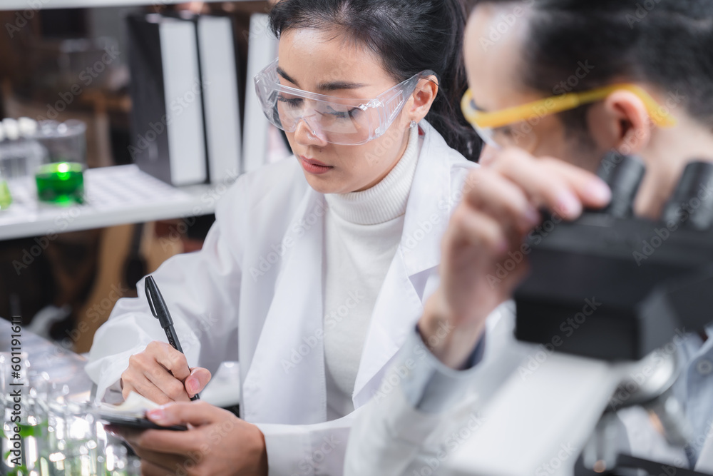 Scientist analyzing microscope slide at laboratory. Young woman ...