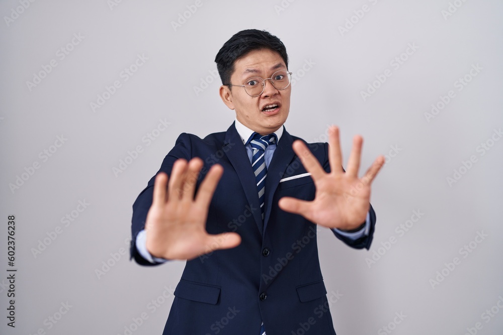 Young asian man wearing business suit and tie afraid and terrified with ...