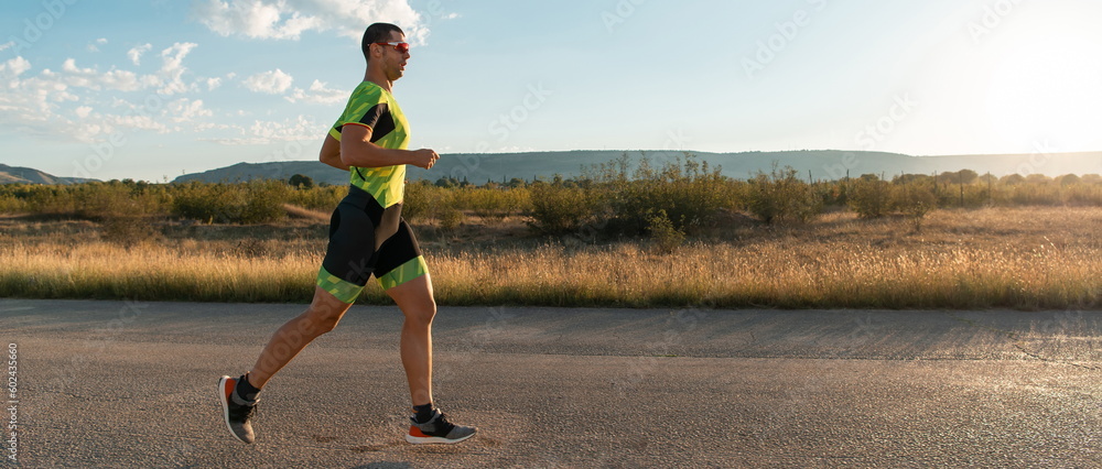 Triathlete in professional gear running early in the morning, preparing ...