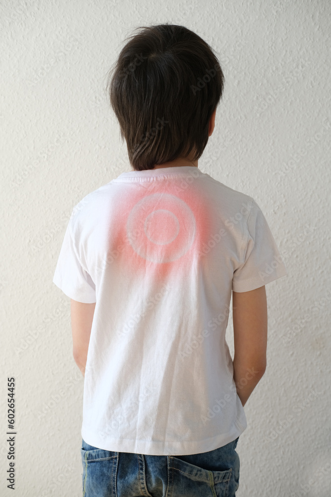 back of boy, child 8-10 years old in a white t-shirt slouches, red spot ...