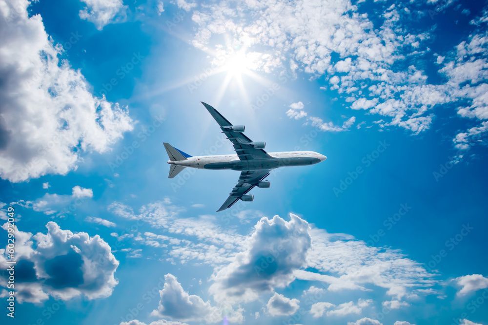 Airplane in the blue sky with clouds from below, high flying passenger ...