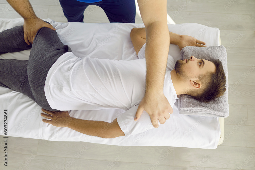Young male osteopath is working on the spinal lumbar region of young ...