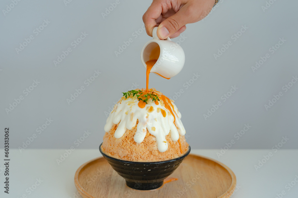 Japanese shaved ice dessert , Hand pouring sweet Thai tea sauce on ...
