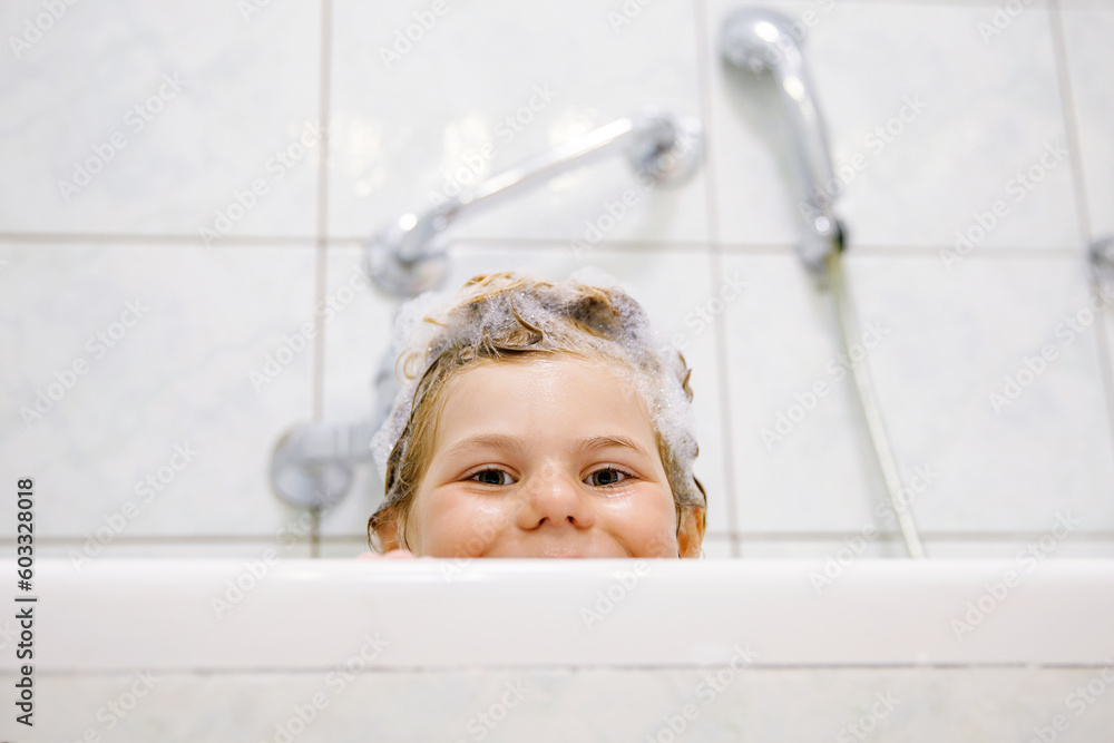 Cute child with shampoo foam and bubbles on hair taking bath. Portrait ...
