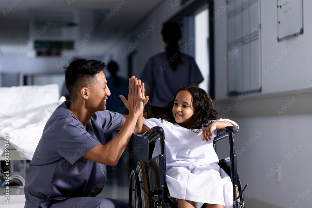 Happy asian male doctor and biracial girl patient in wheelchair high ...