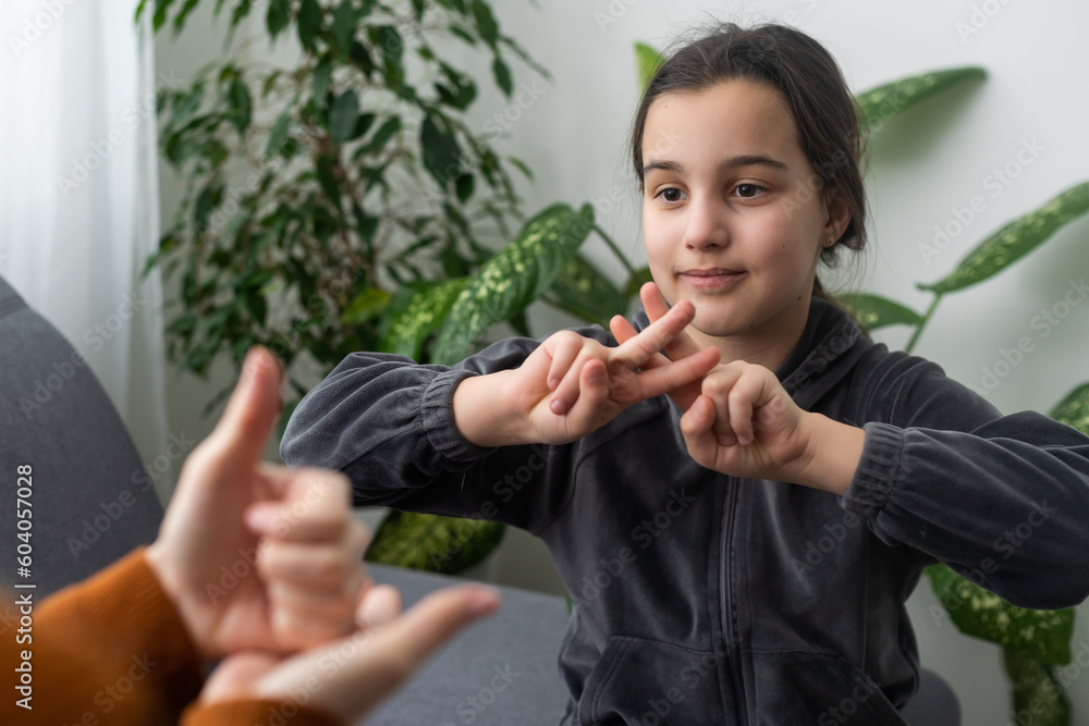 Cute little girl make hand gesture learning sign language with mom or female nanny, smiling ...