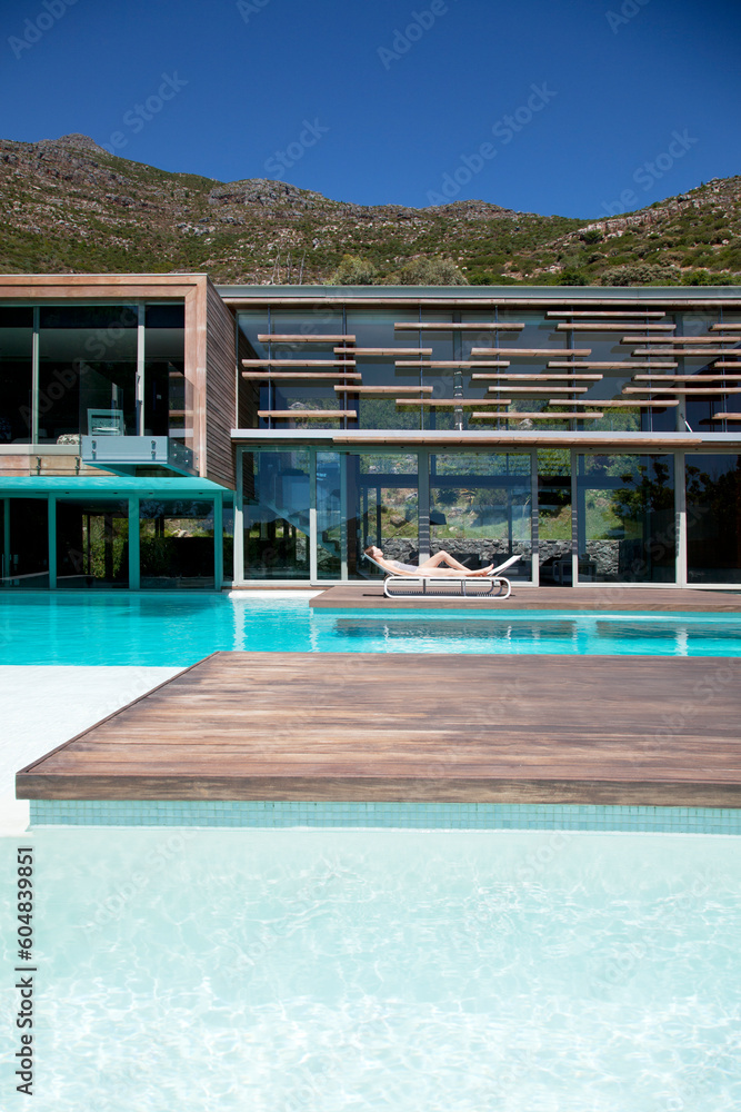 Woman sunbathing poolside of modern house Stock Photo | Adobe Stock