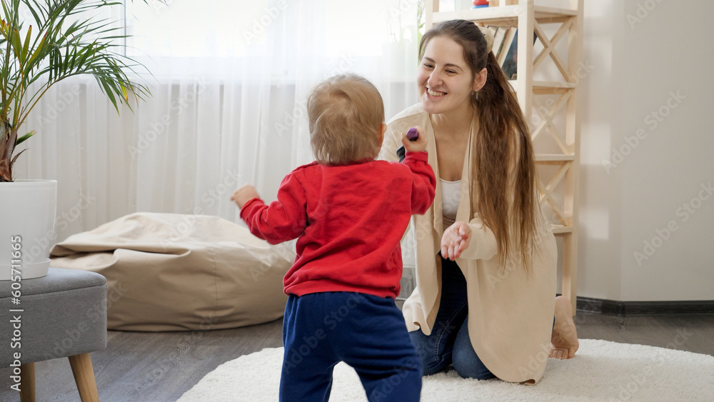 Cute baby boy learning walking and making steps to his mother sitting ...