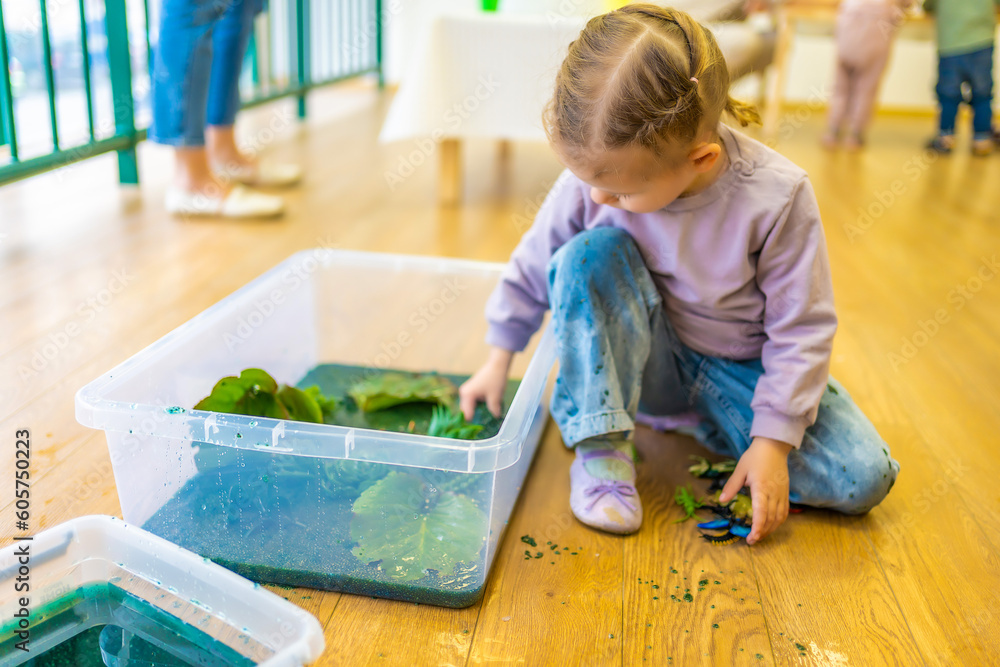 Little girl playing in handmade swamp of green-dyed chia seeds with ...
