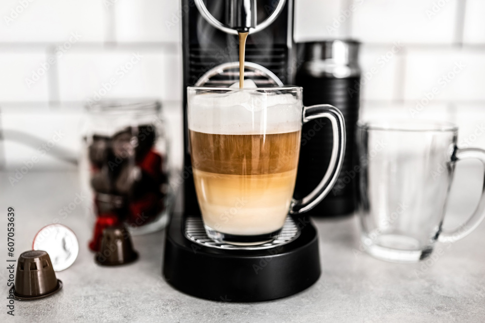 Coffee machine with capsules and creamy cappuccino in transparent cup ...