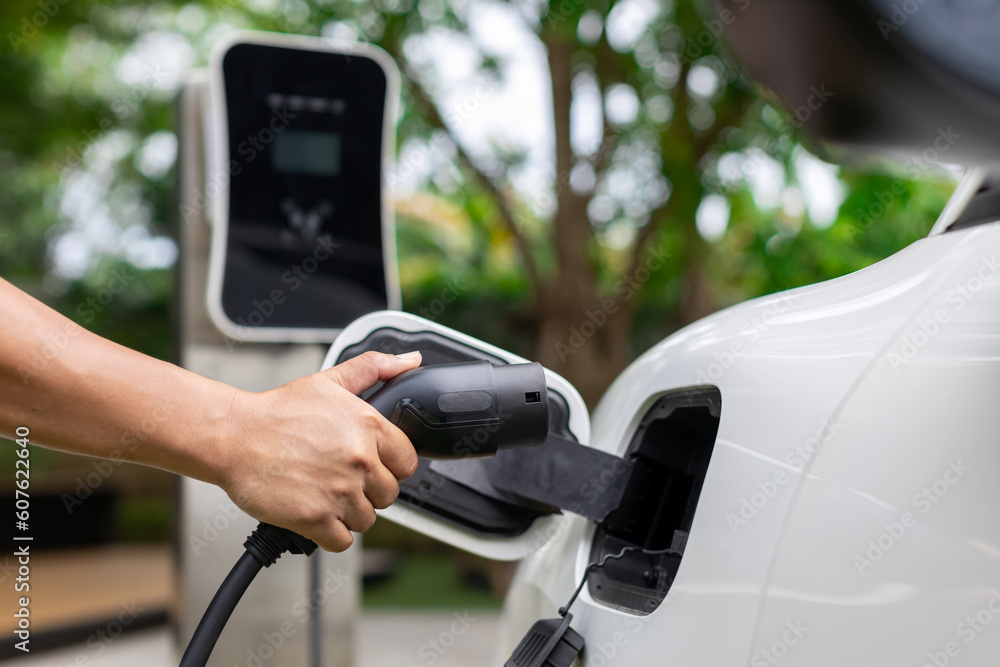Hand inserting EV charging plug to electric vehicle in focus shot with ...