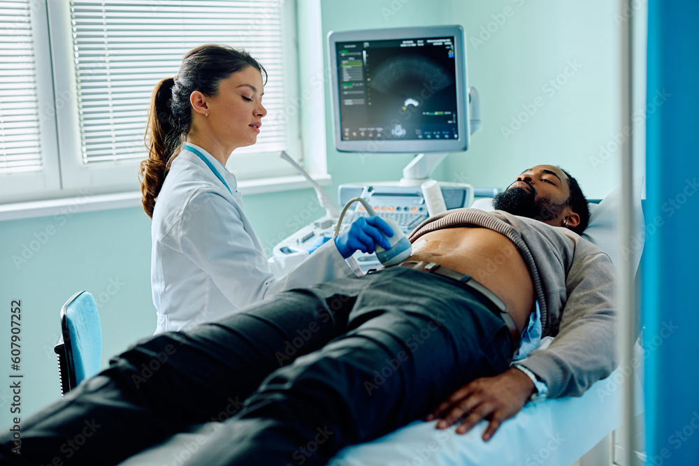 Female doctor examining black man's abdomen with ultrasound at medical ...