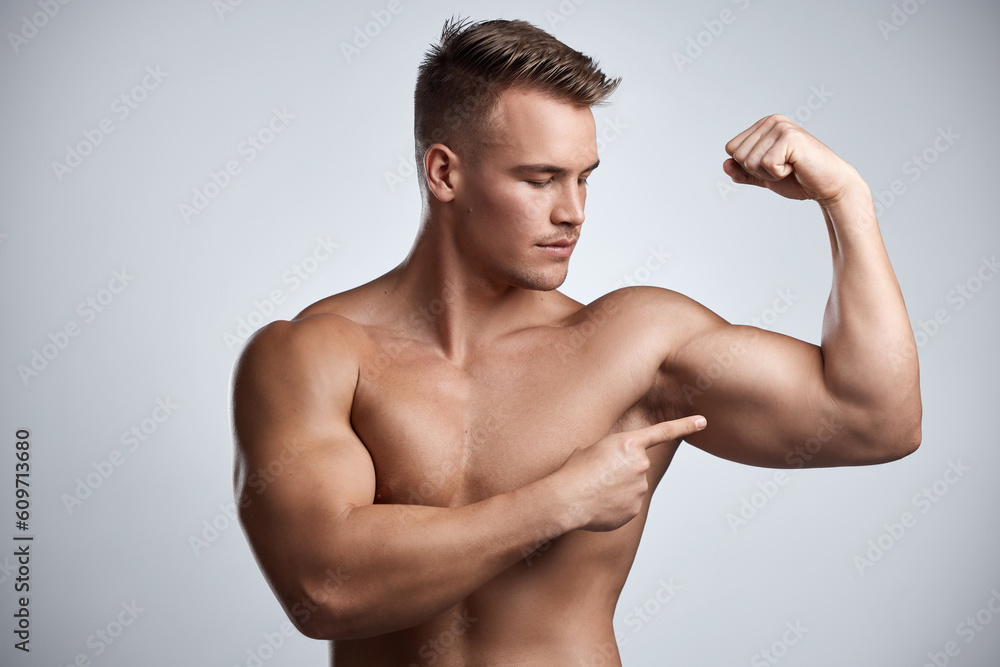 Man, bodybuilder and pointing to bicep in studio, background and ...