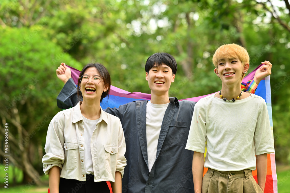 Image of young people with LGBTQ pride flag, standing in public park ...