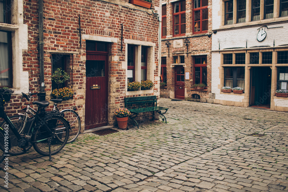 old european brick building edifice with dark red door a green bench ...