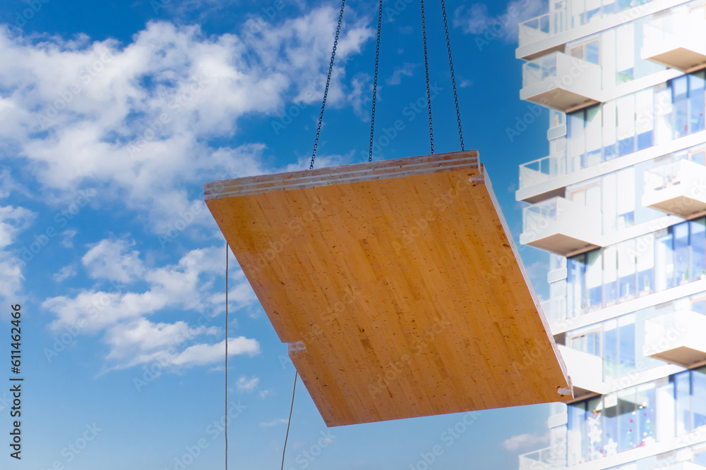 A crane lifting a pre-fabricated glue laminated panel onto a mass ...
